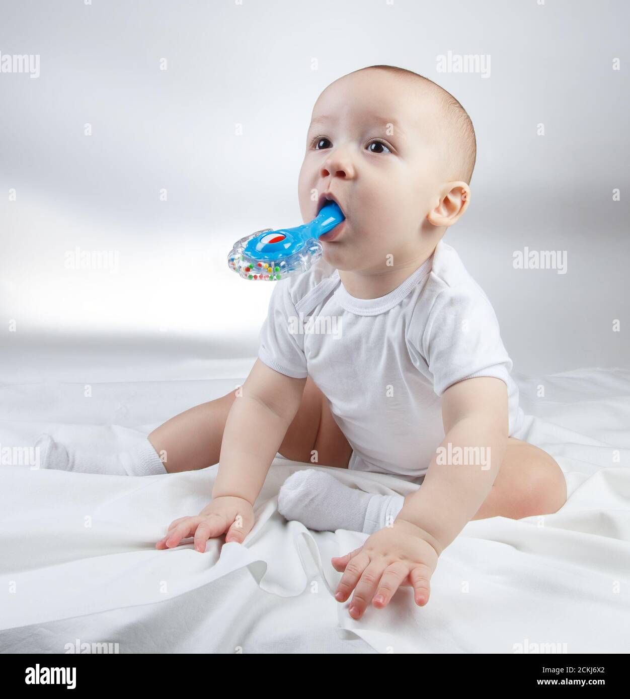 Image of a ten-month-old baby with blue rattle in mouth Stock Photo - Alamy