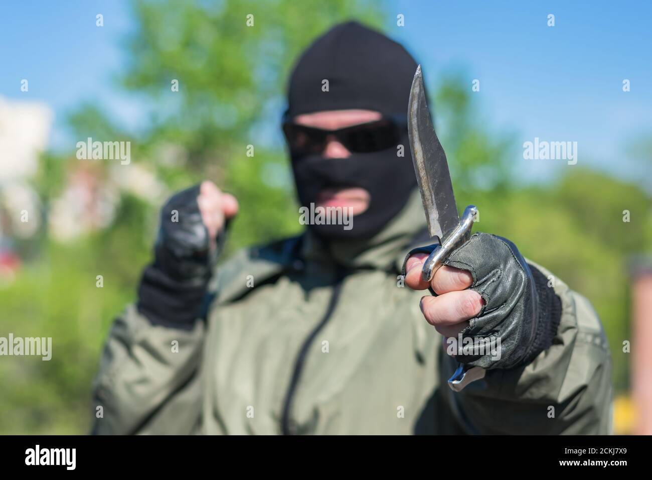 A hunting knife in the hands of a man in a balaclava Stock Photo - Alamy