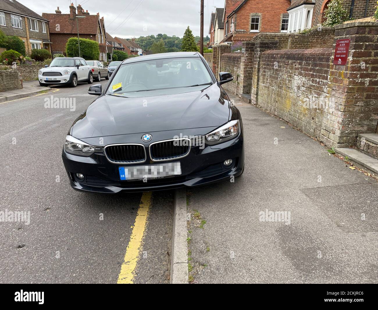 A car parked on a pavement in Surrey, England. The blocking of ...