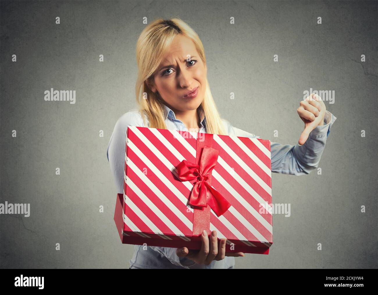 Closeup portrait young woman holding, opening gift box, displeased ...