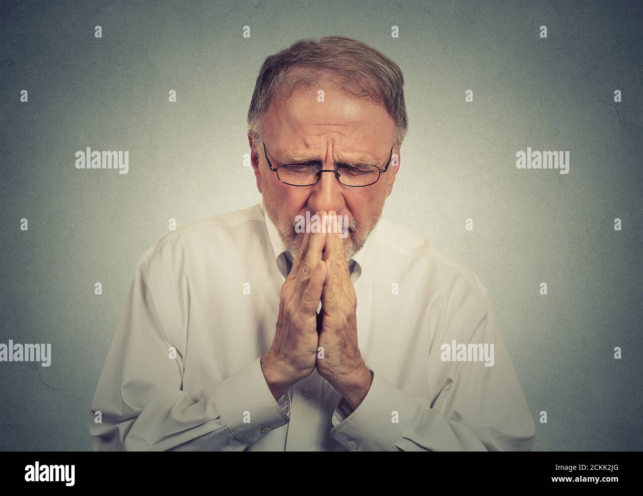 Headshot serious senior man concentrating isolated on gray wall ...
