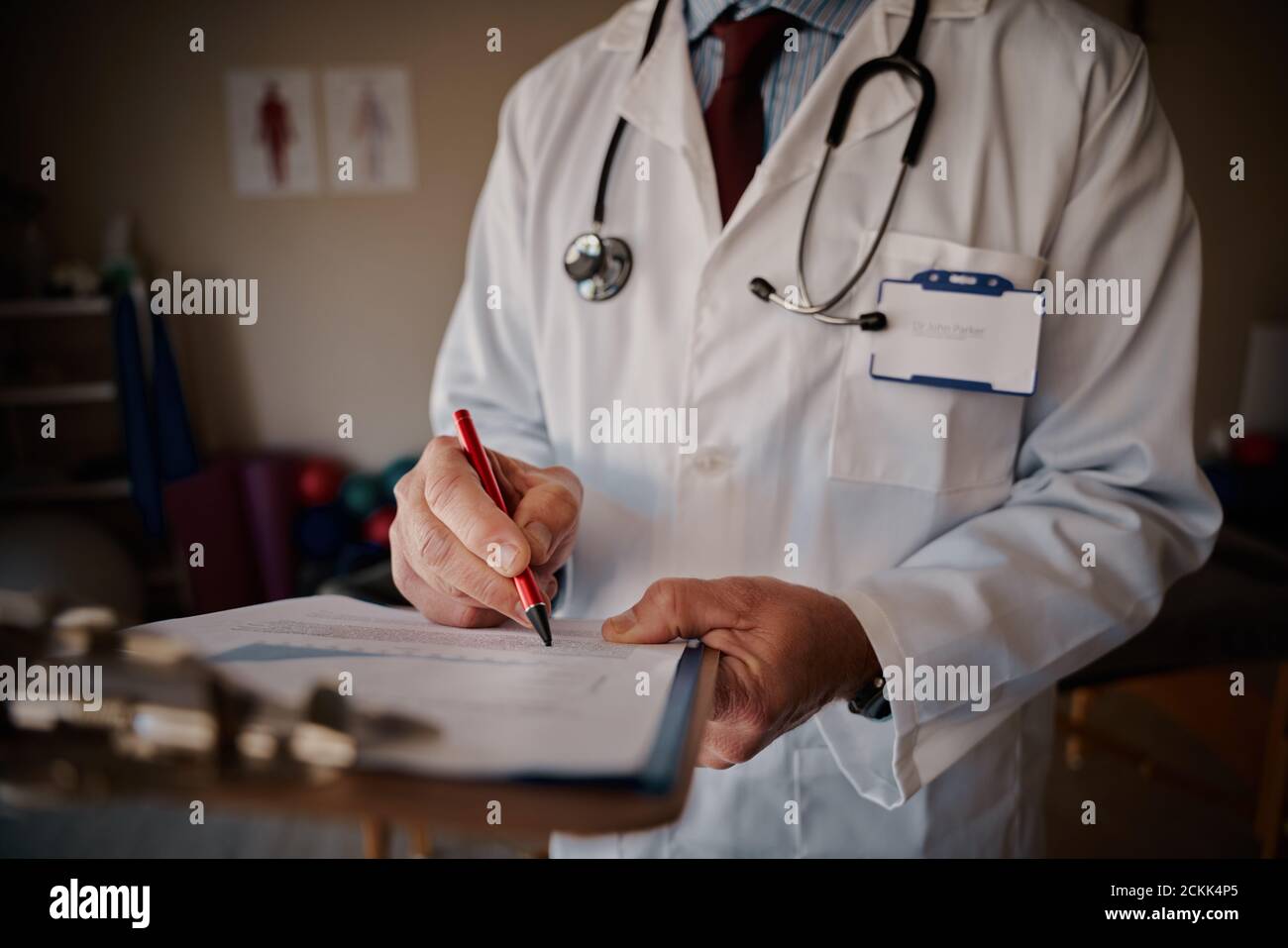 Closeup of senior male doctor writing notes on the clipboard in the ...