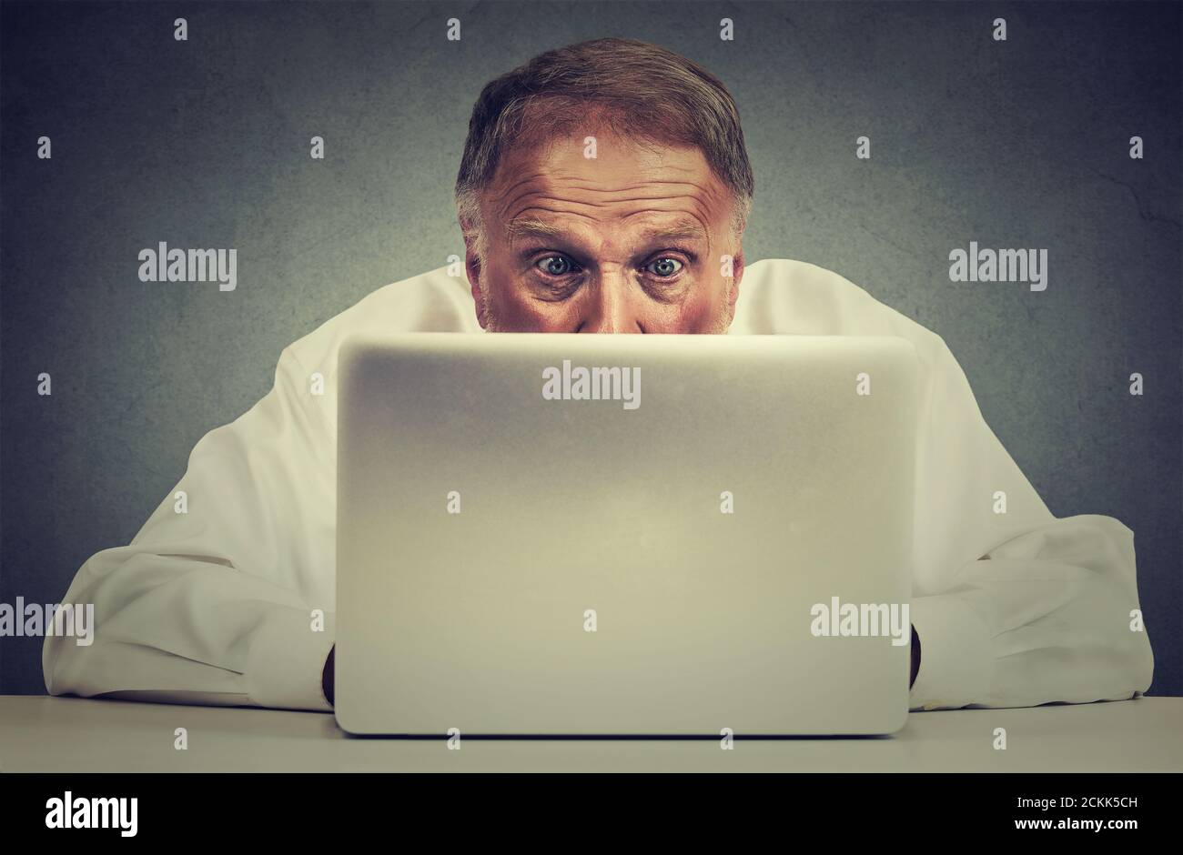 Closeup portrait elderly surprised man sitting at table working on ...