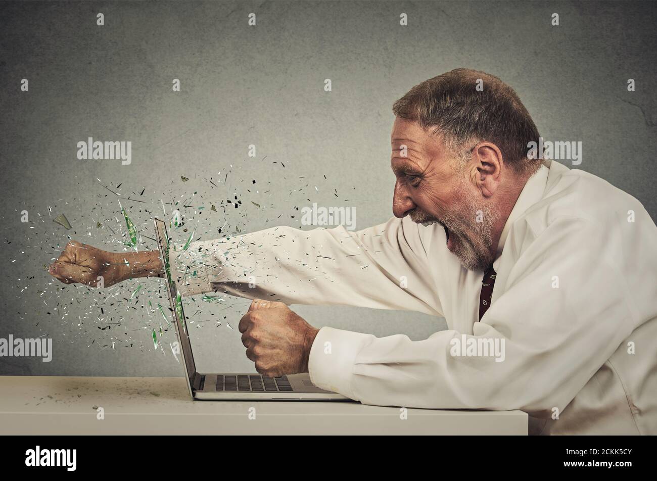 furious senior businessman throws punch into computer screaming ...