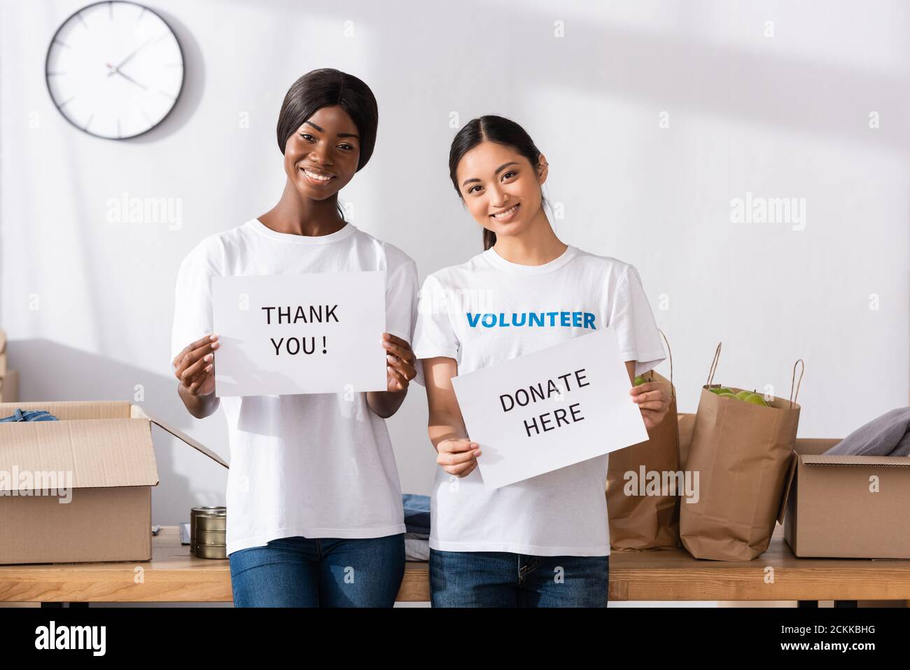 Multicultural volunteers holding cards with donate here and thank you ...