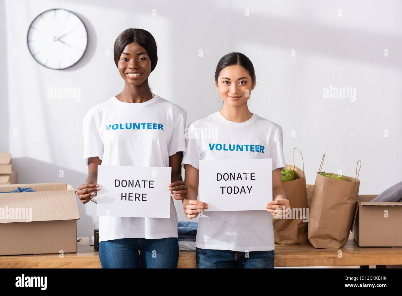 African american and asian volunteers holding cards with donate today ...