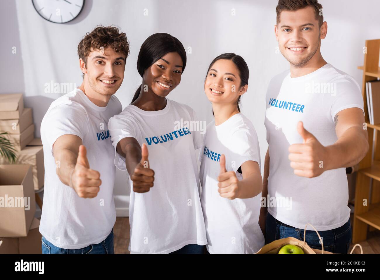 Multicultural volunteers showing like gesture in charity center Stock ...