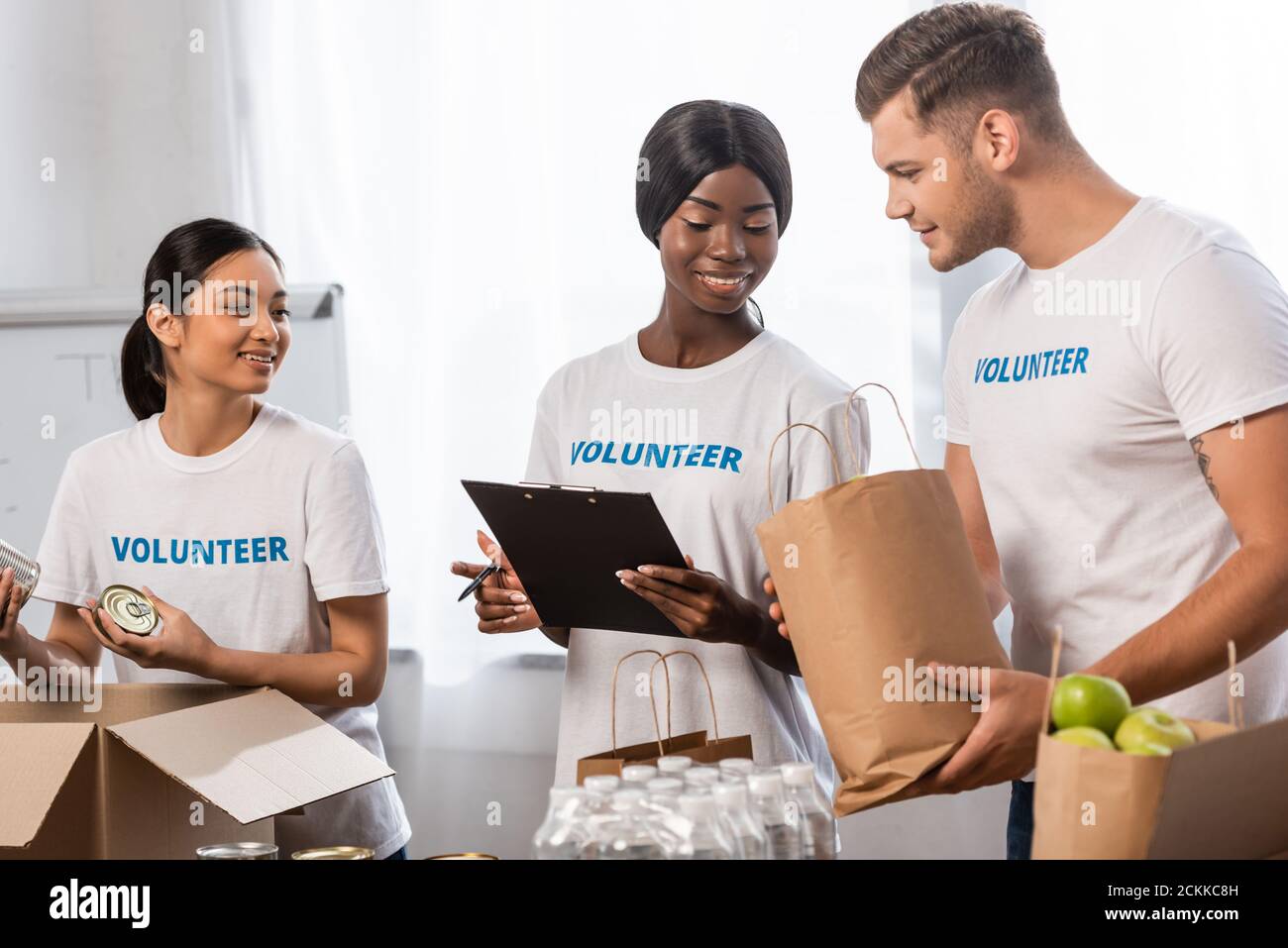 Multicultural volunteers holding packages with food near african ...