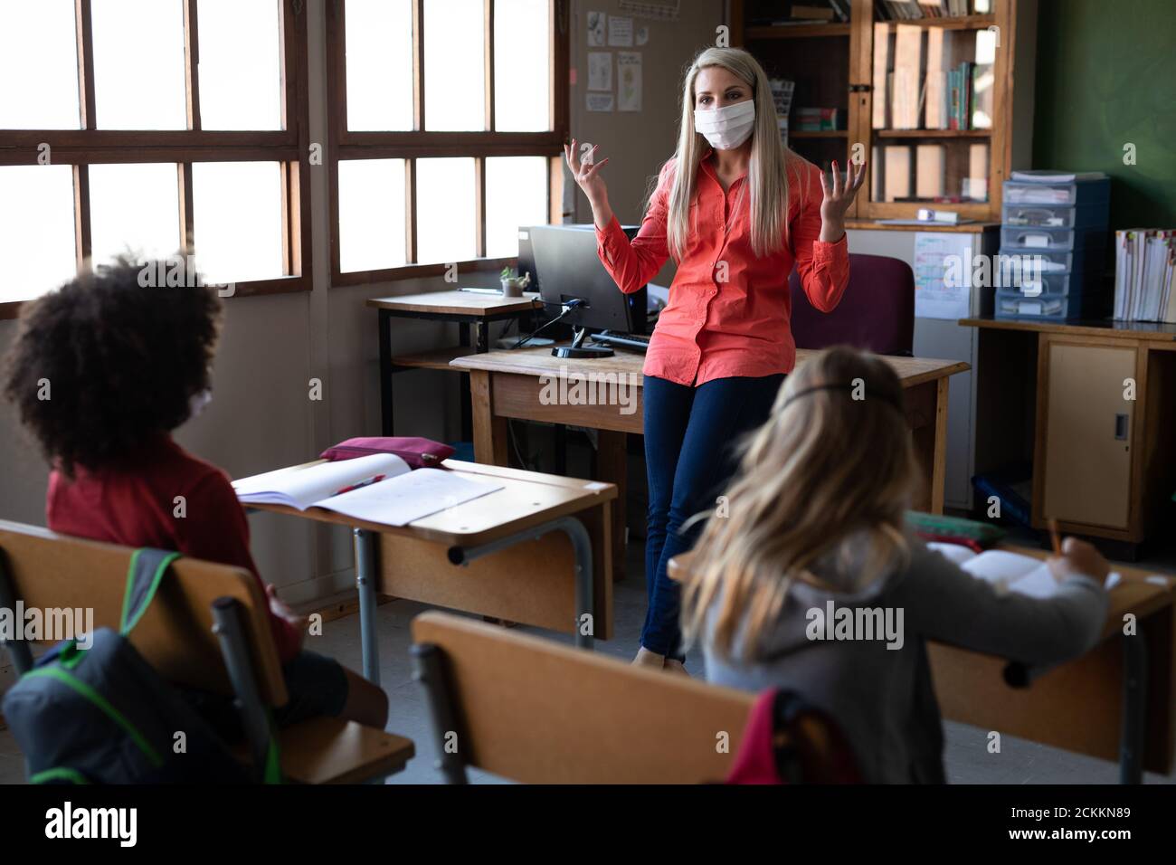 Female teacher wearing face mask teaching in class at school Stock ...
