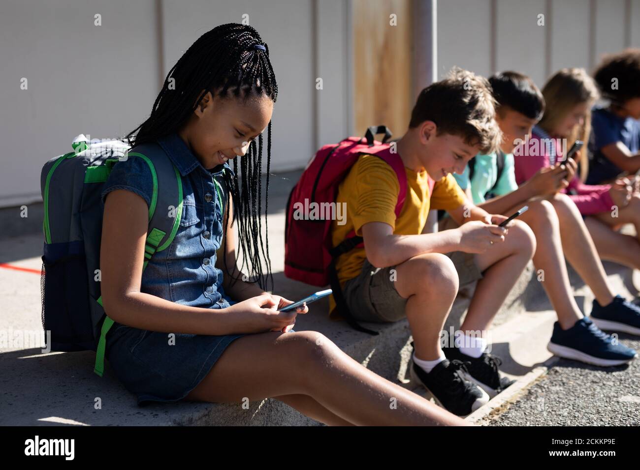 Group of kids using smartphones while sitting together Stock Photo - Alamy