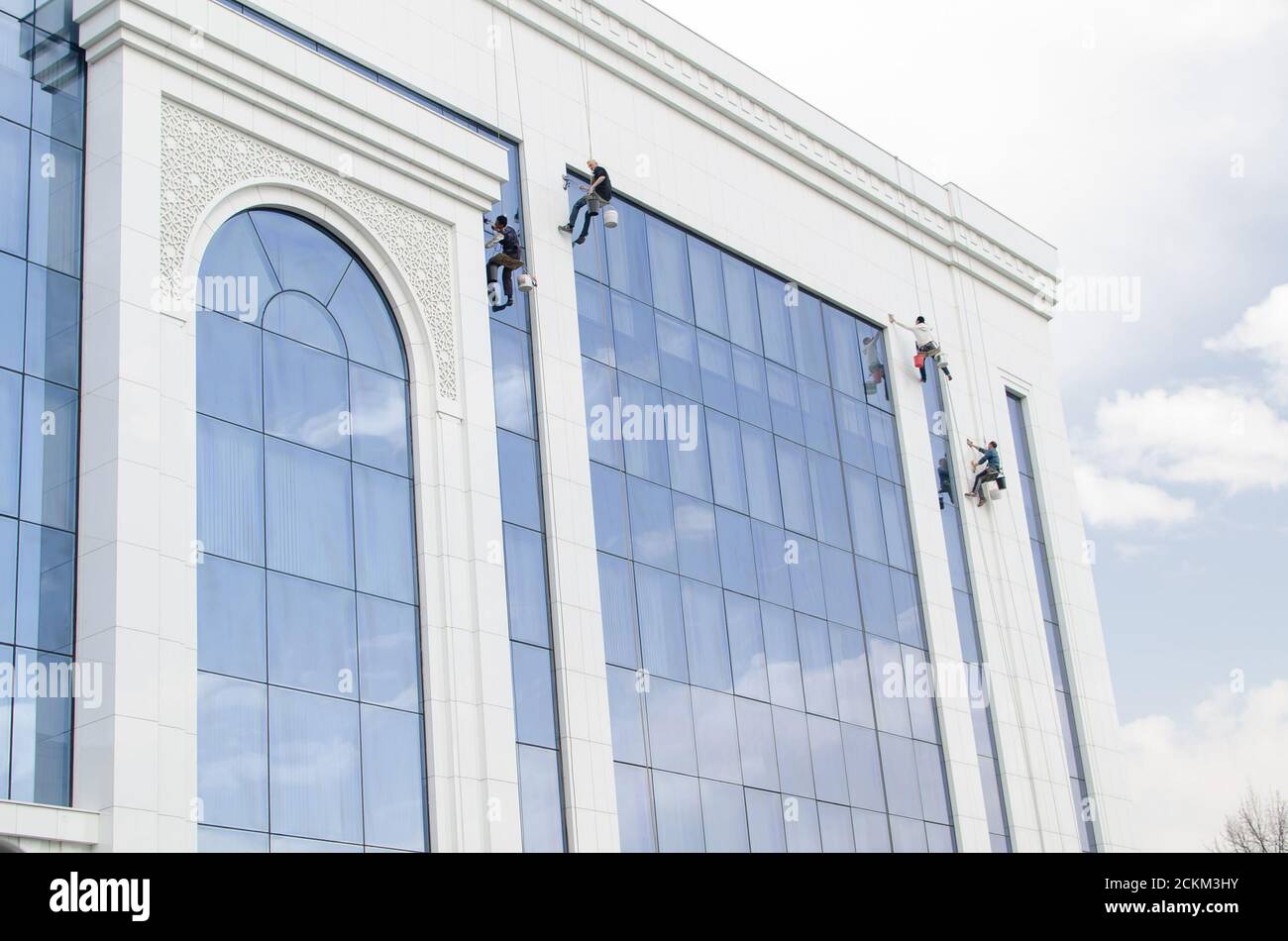 Four people, high-rise climbers, wash a beautiful building with blue ...