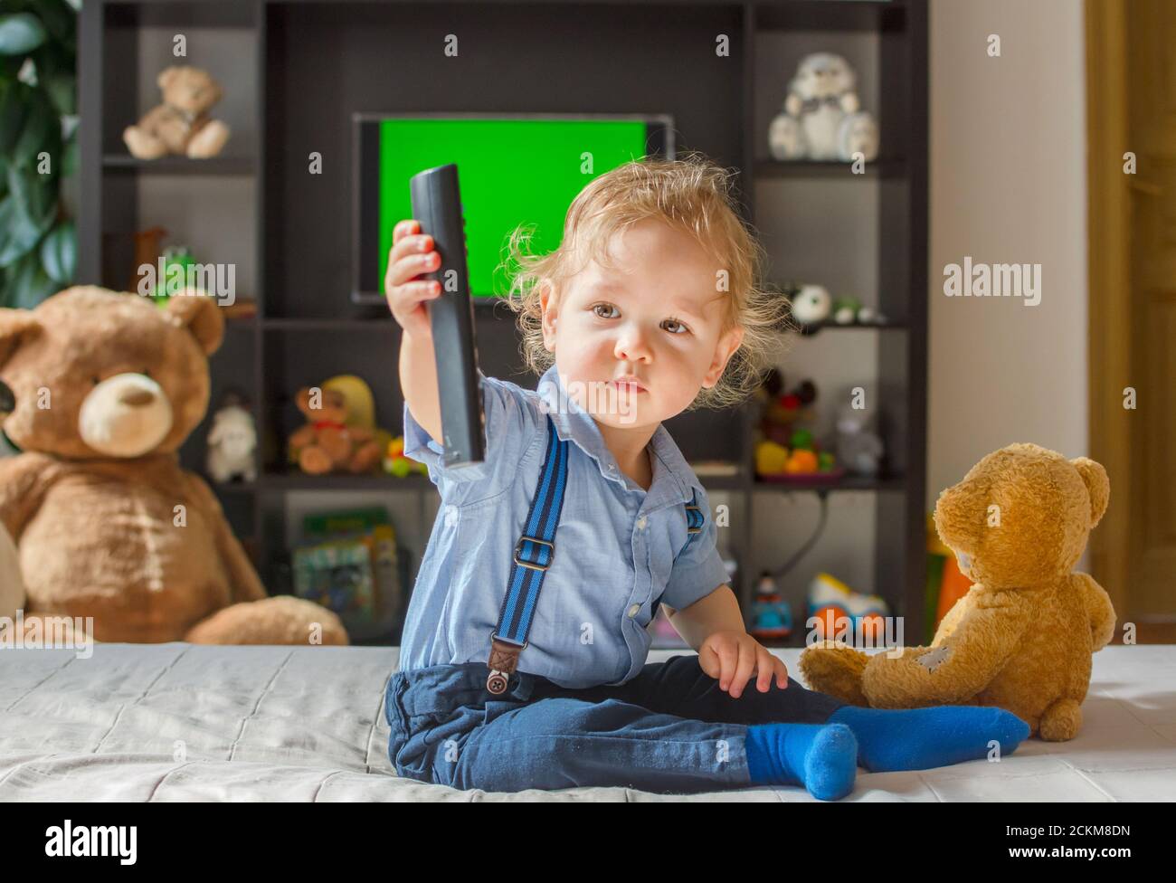 Cute baby boy playing with the remote control to watch TV sitting on a ...