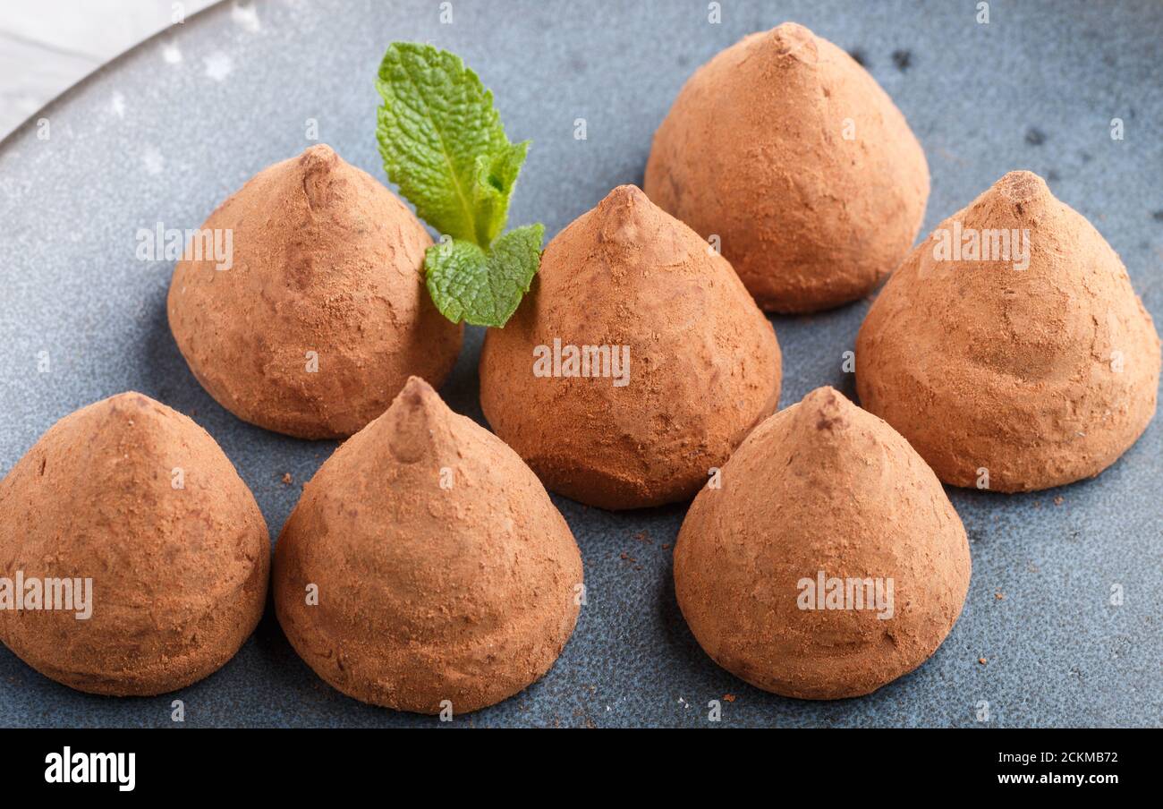 Chocolate truffle on blue ceramic plate on gray concrete background ...
