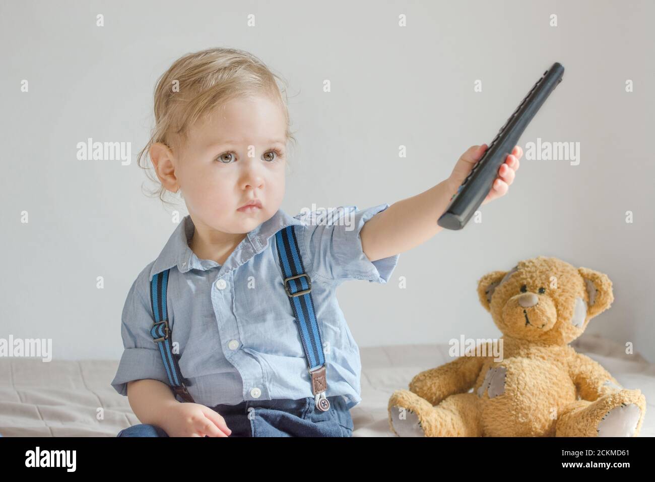 Cute baby boy playing with the remote control to watch TV sitting on a ...