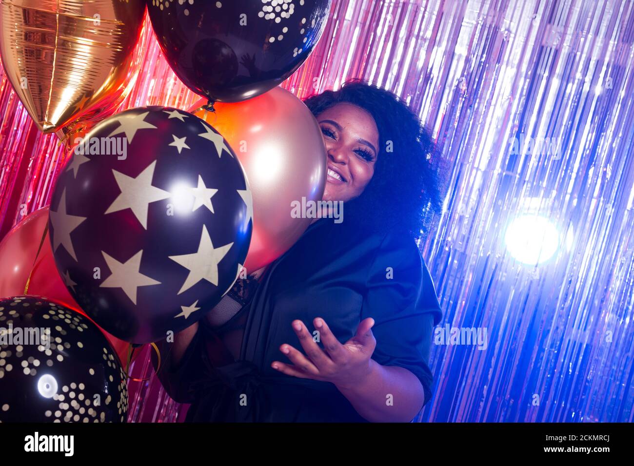 Young black woman looks happy while spend time in night club. Birthday ...