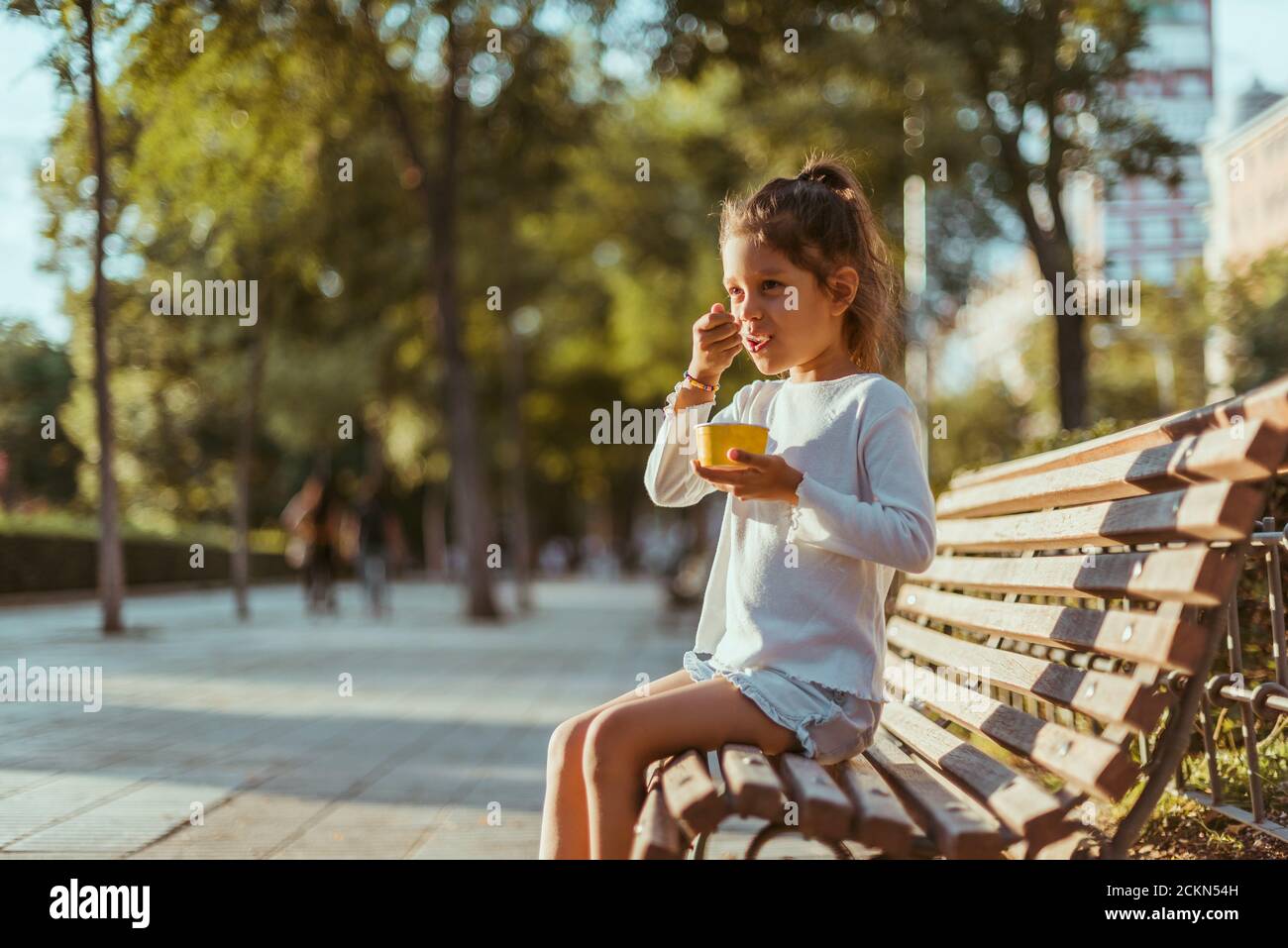 Child eating ice cream on a park bench Stock Photo - Alamy