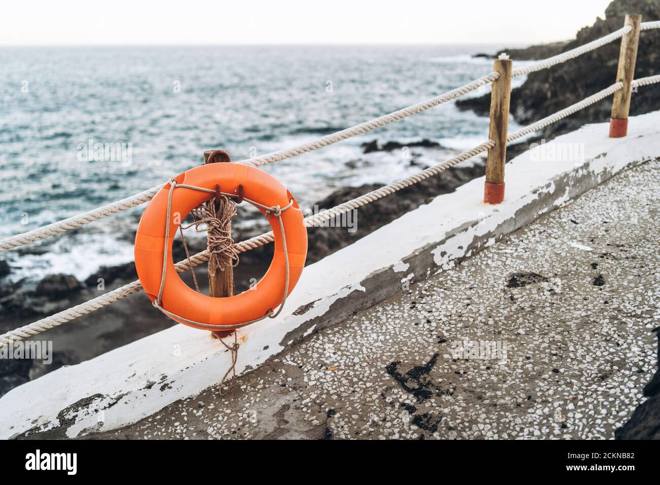 Red emergency lifebuoy hanging on fence near beach Stock Photo - Alamy