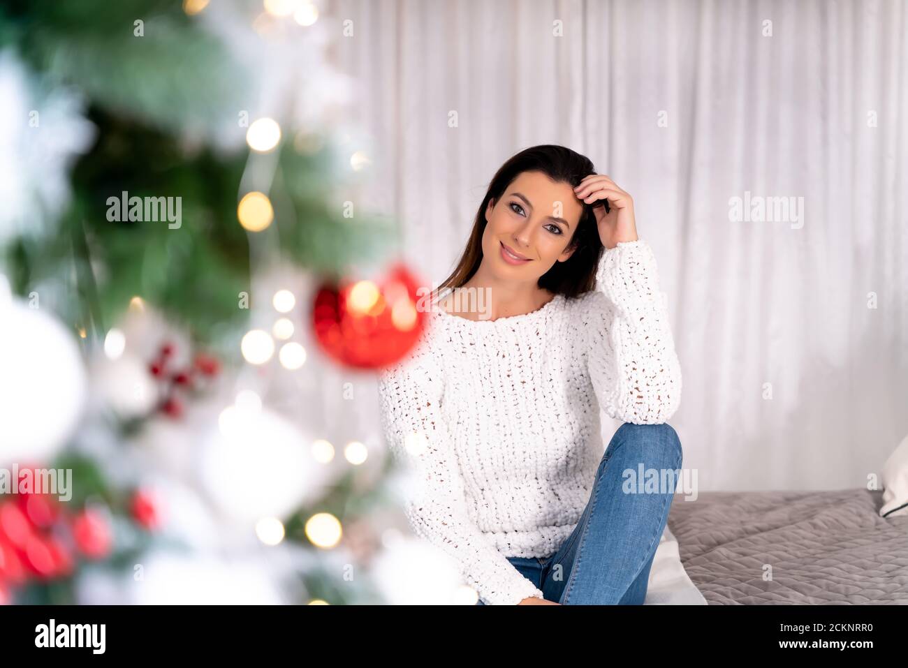 A beautiful woman alone at home during Christmas season beside a ...
