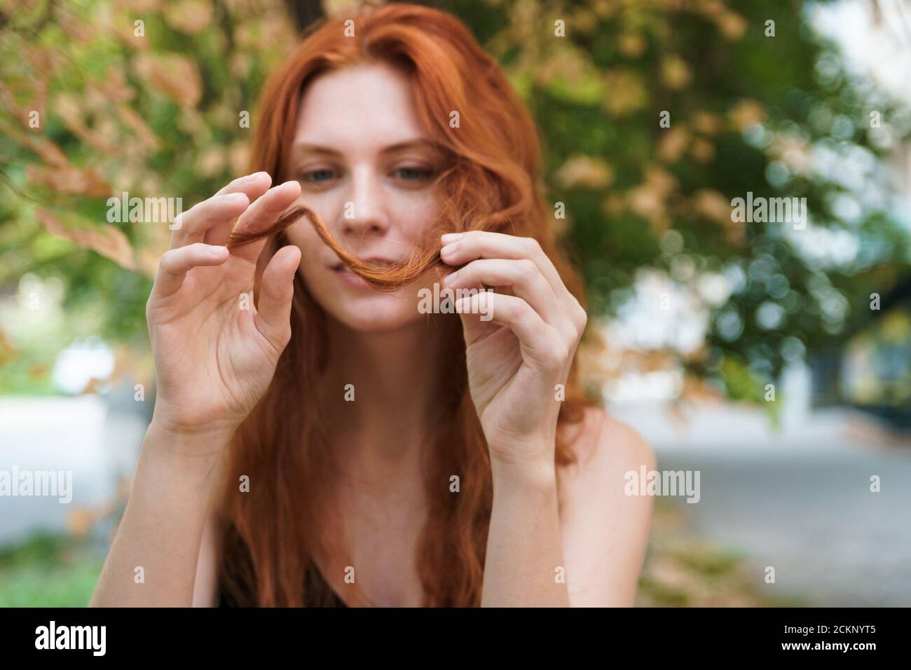 Ginger girl with long hairs in hand. Young woman with blurred face ...