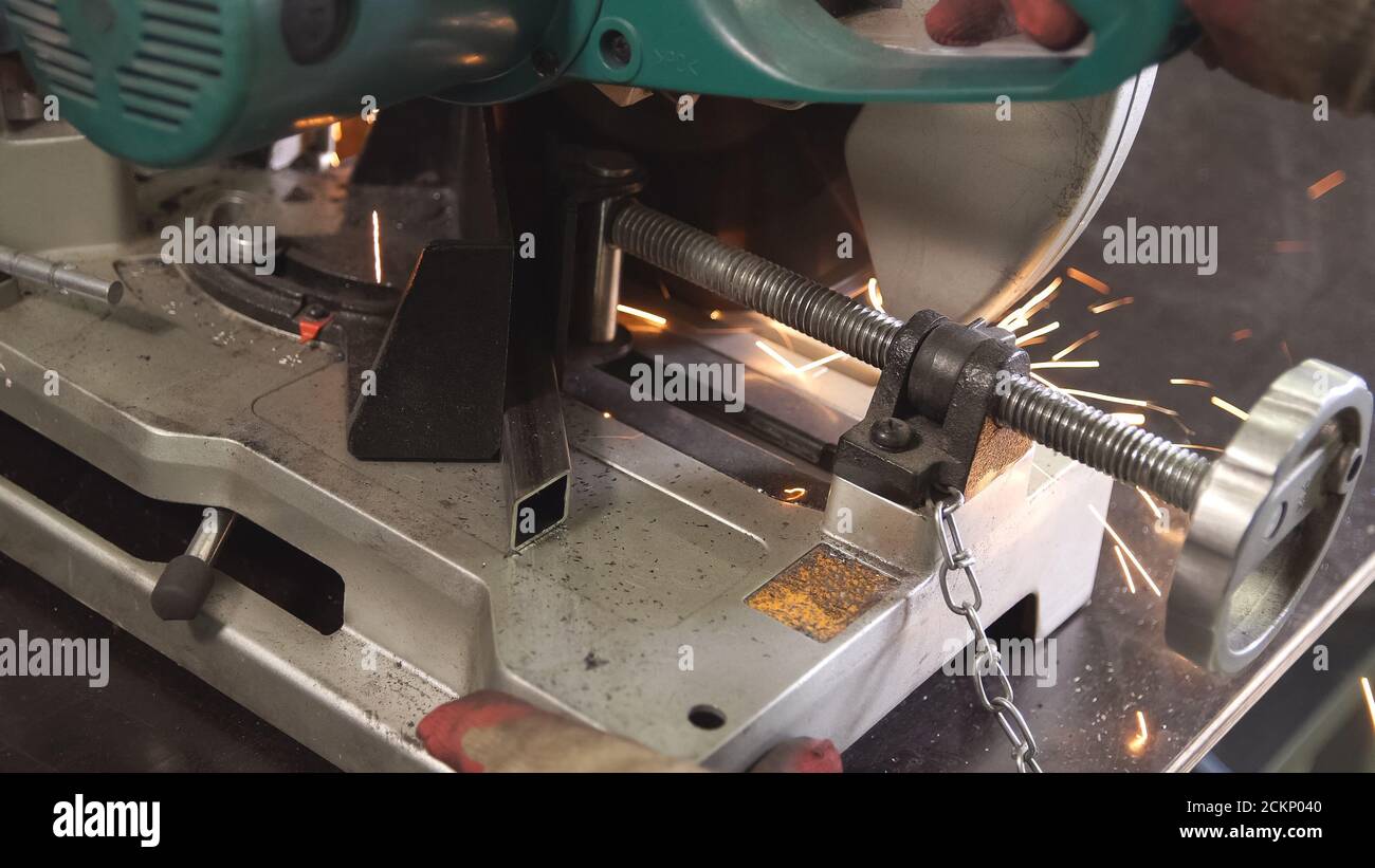 Grinding in steel manufactory. Working man with big saw cutting metal ...