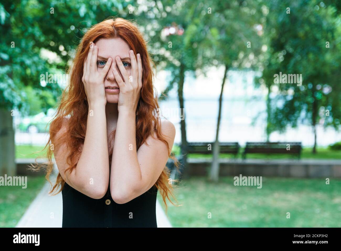 Young ginger woman hide her face by hands outdoor Stock Photo - Alamy