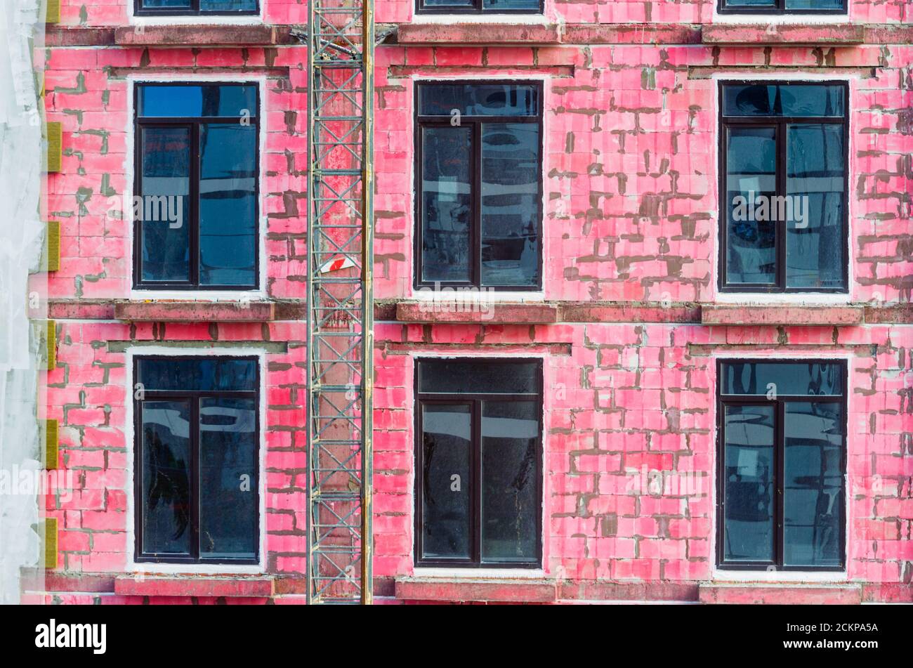 Windows of a house under construction from cinder blocks painted red ...