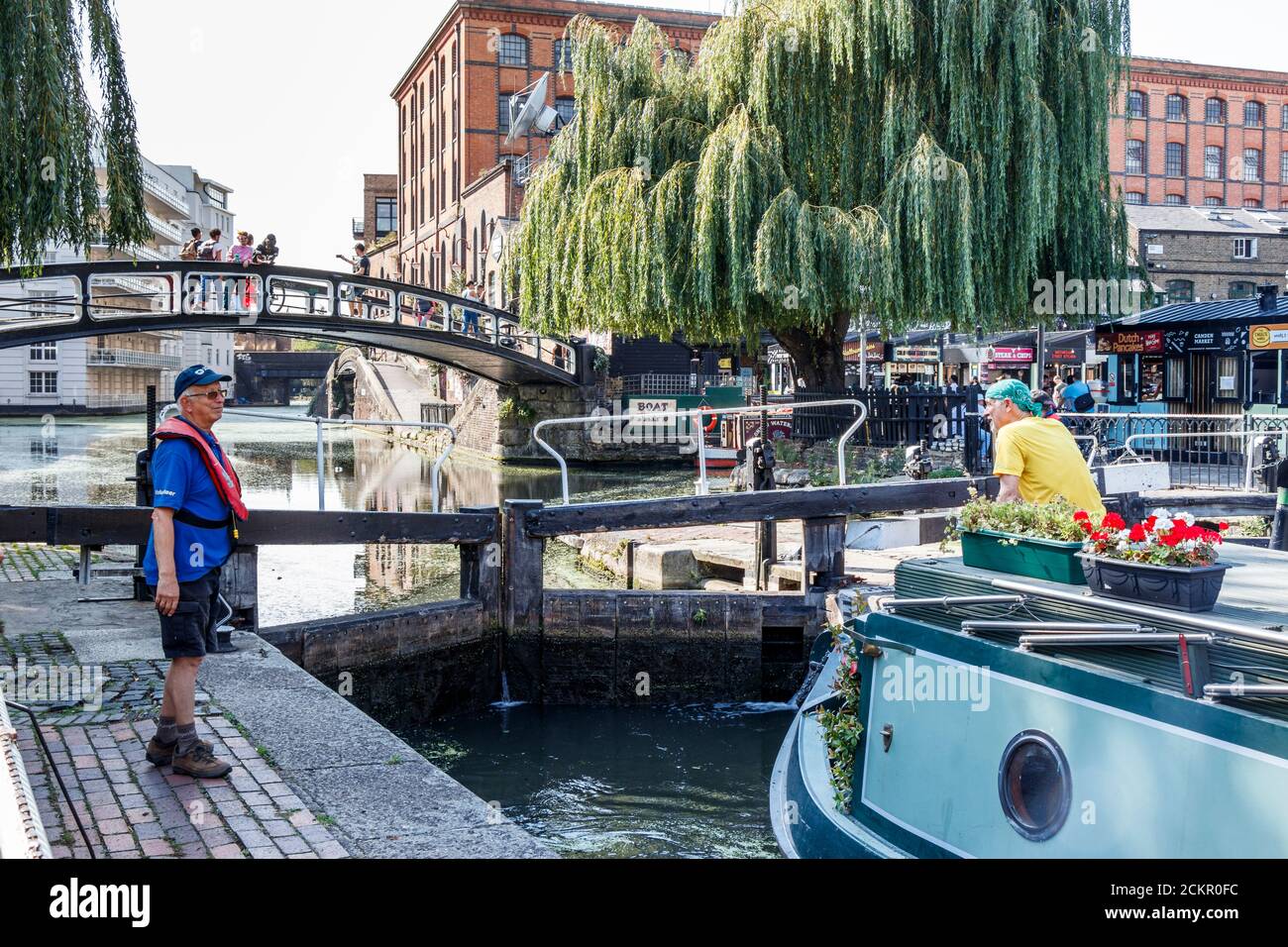 A volunteer lock keeper helps out as a narrowboat passes through the ...