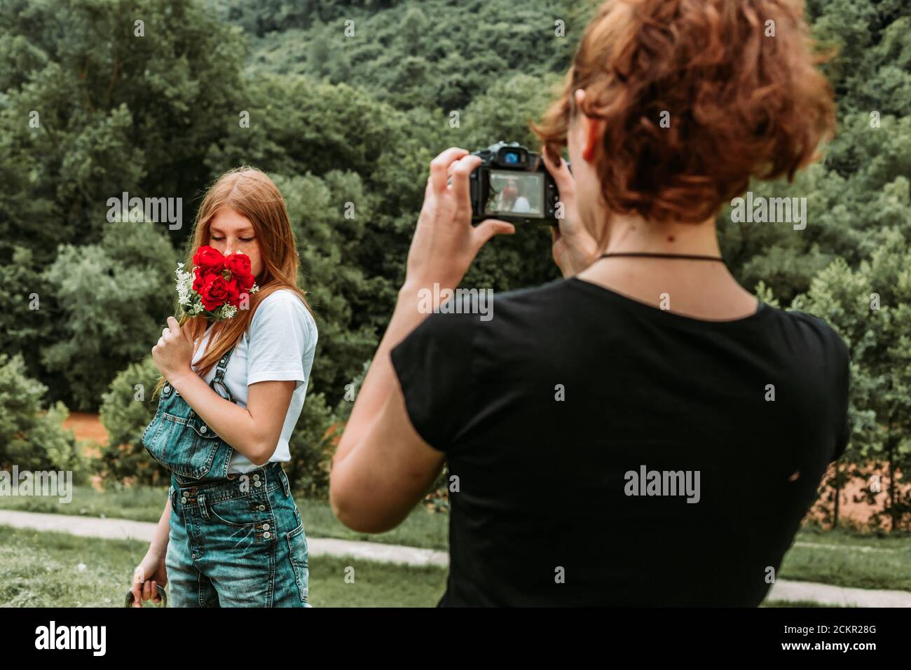 Female photographer taking photos of beautiful teen ginger girl holding ...