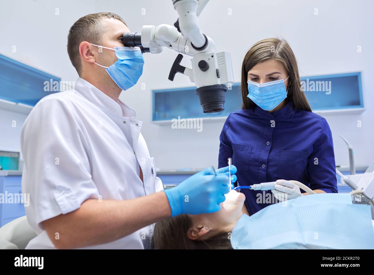 Male doctor dentist treating teeth using dental microscope instruments ...
