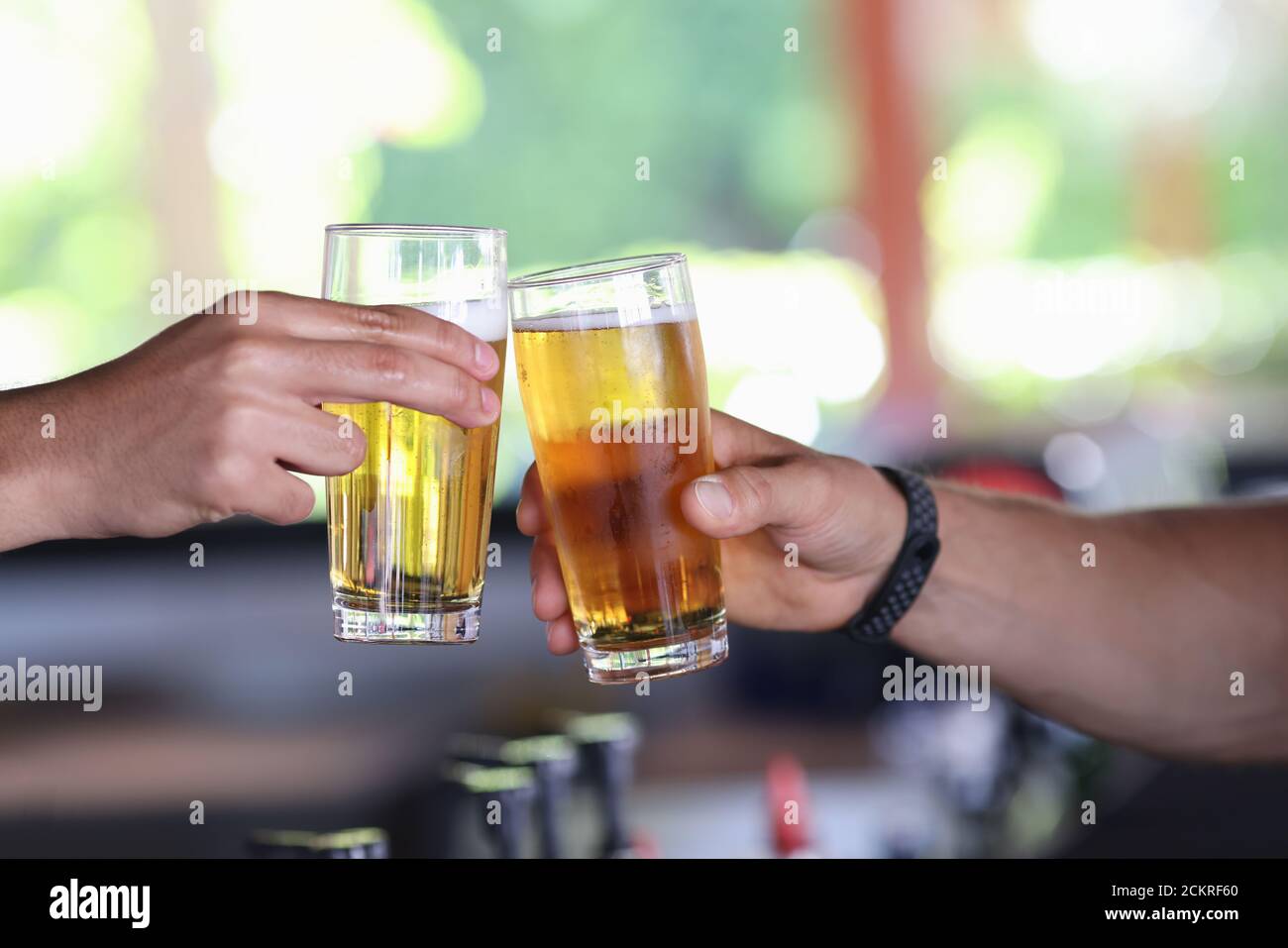 Two male hand hold glass of cold beer and clink glasses Stock Photo - Alamy