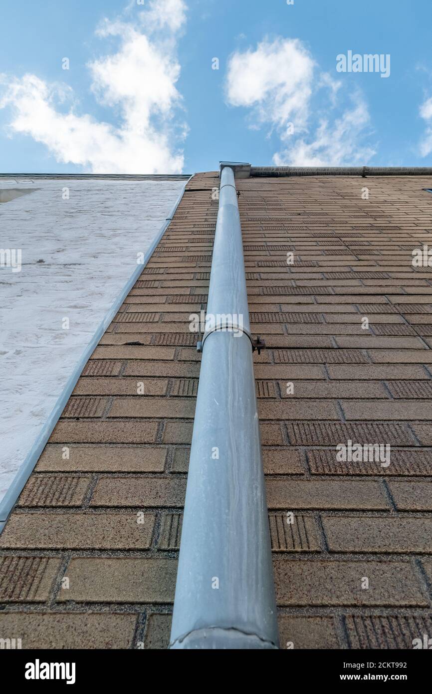 Vertical shot of a rainwater pipe attached on a brick wall going up ...