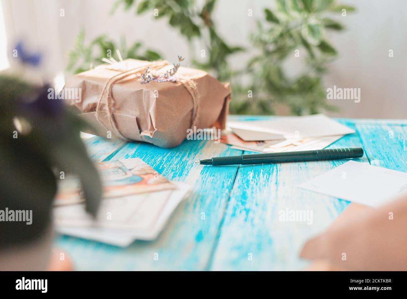 Composition of postcards, pen and parcel. Side view. Blue wooden ...