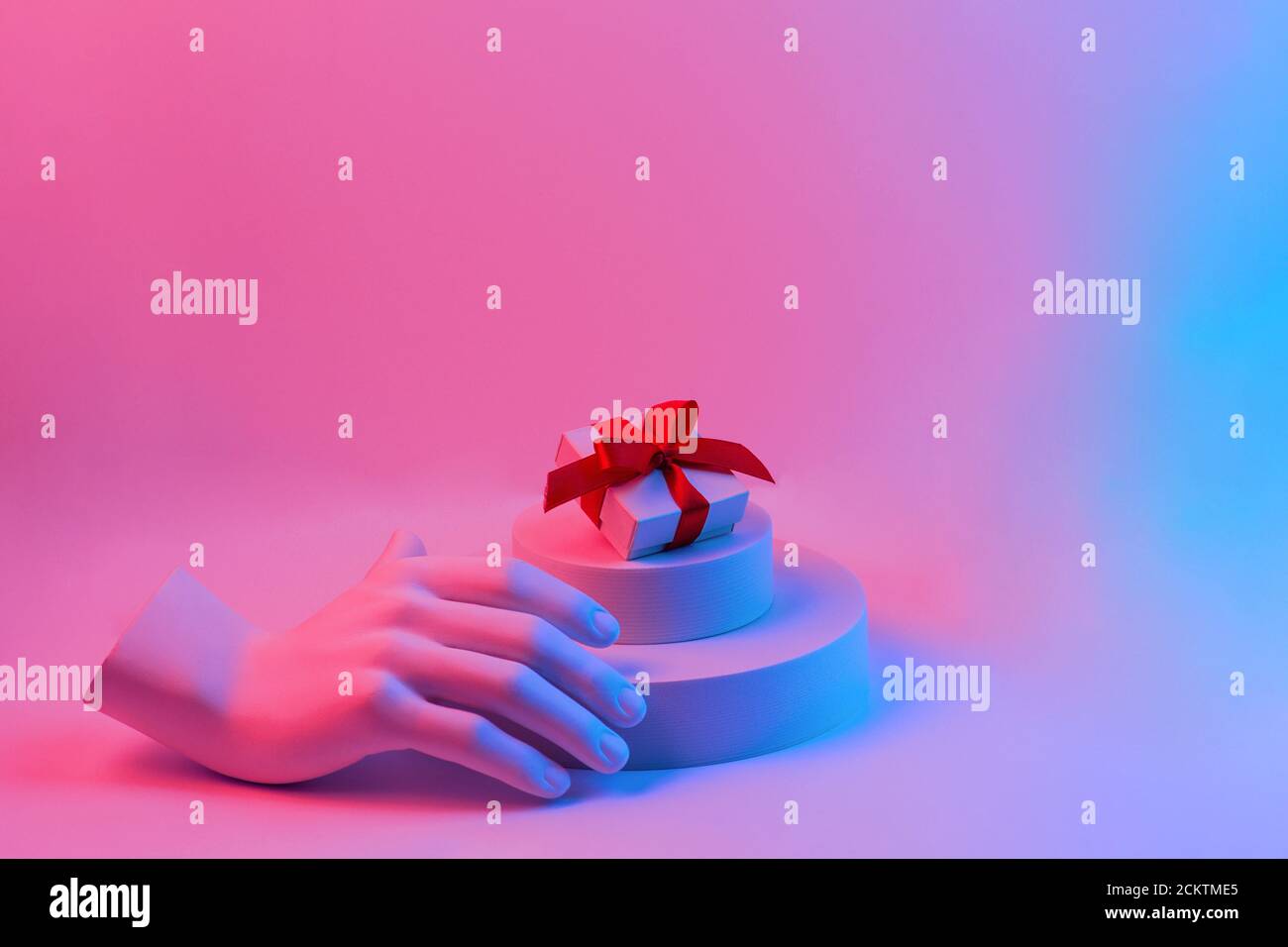 Composition with gypsum hand. A box with a red ribbon on the podium ...