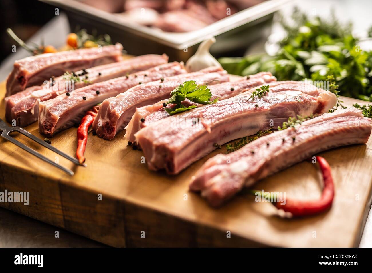 Raw seasoned spare ribs on a cutting board with chillies next to it ...