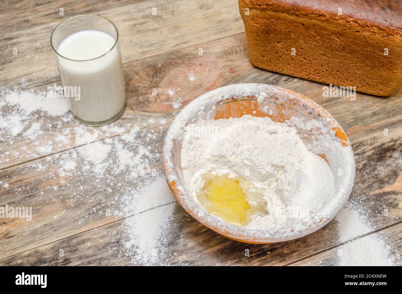 Fresh bread brick on the table closeup. Next is a bowl of flour and egg ...