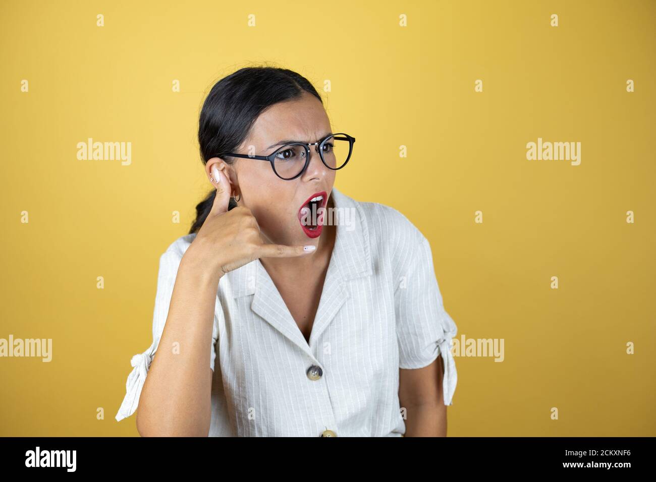 Beautiful woman over yellow background doing phone gesture with hand ...