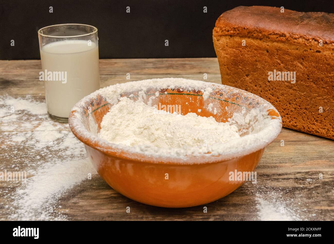 Fresh bread brick on the table closeup. Next is a bowl of flour, a ...