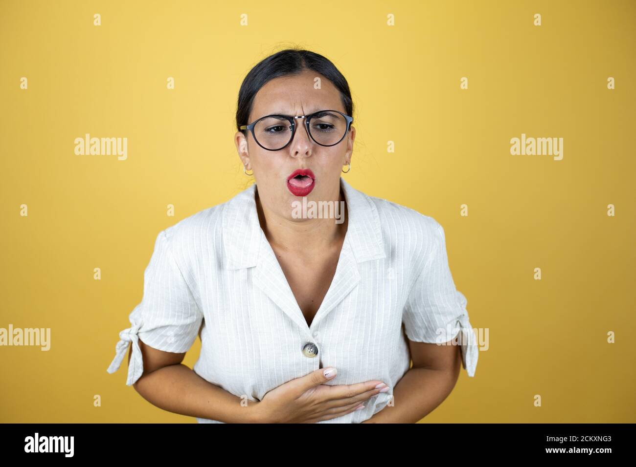 Beautiful woman over yellow background having a nausea Stock Photo - Alamy