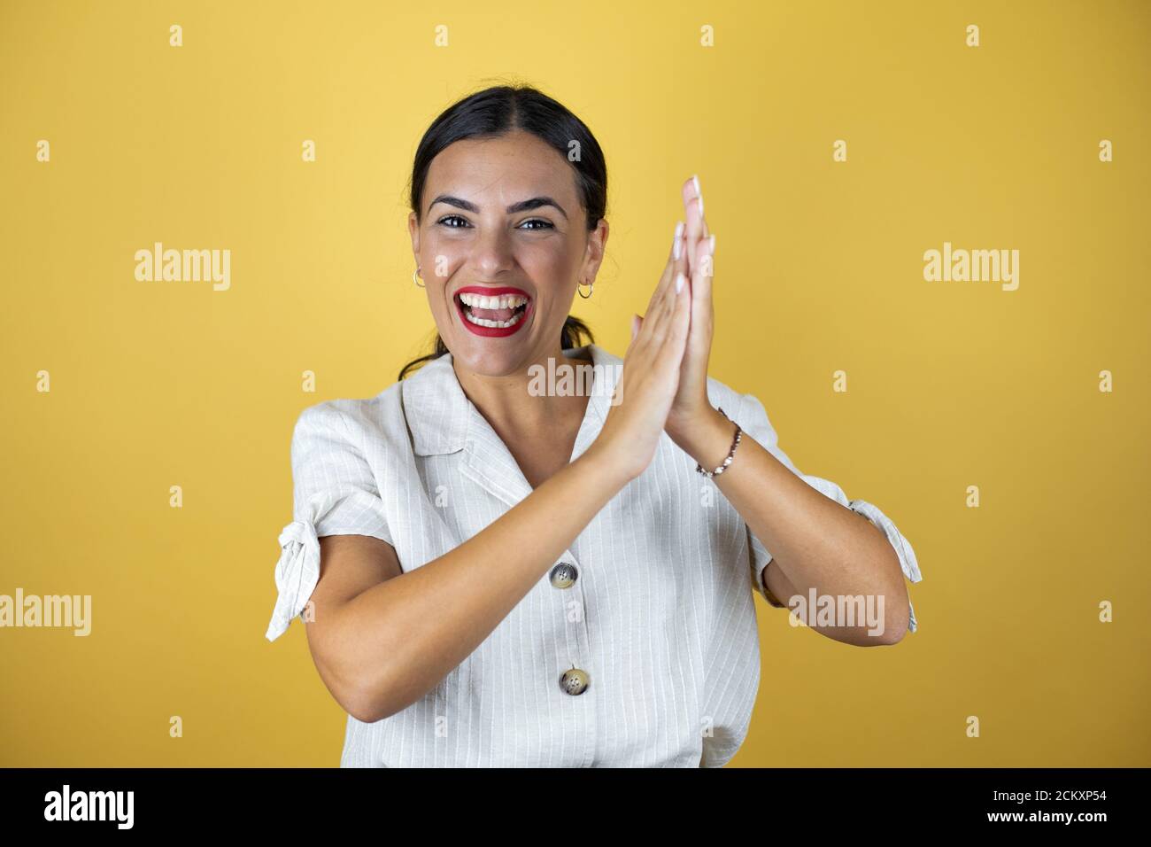 Beautiful woman over yellow background clapping and applauding happy ...