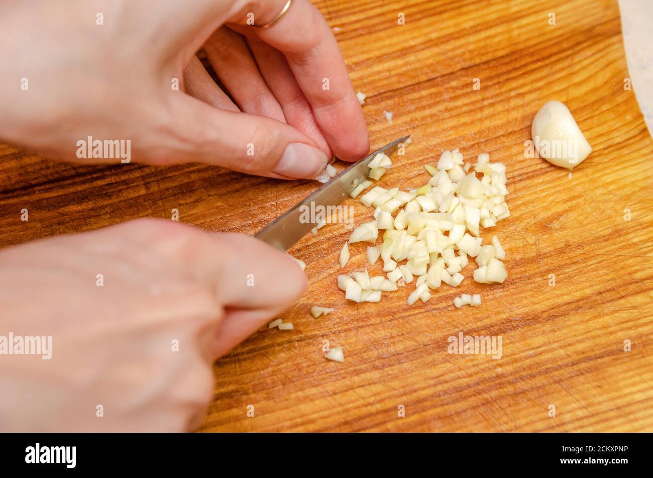 Woman chopping garlic with a knife on a wooden plank closeup Stock ...