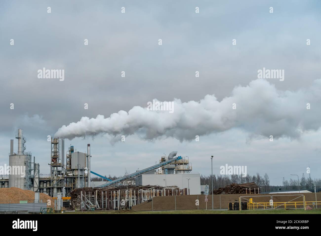 Woodworking plant, thick smoke from the pipes against the gray-blue sky ...