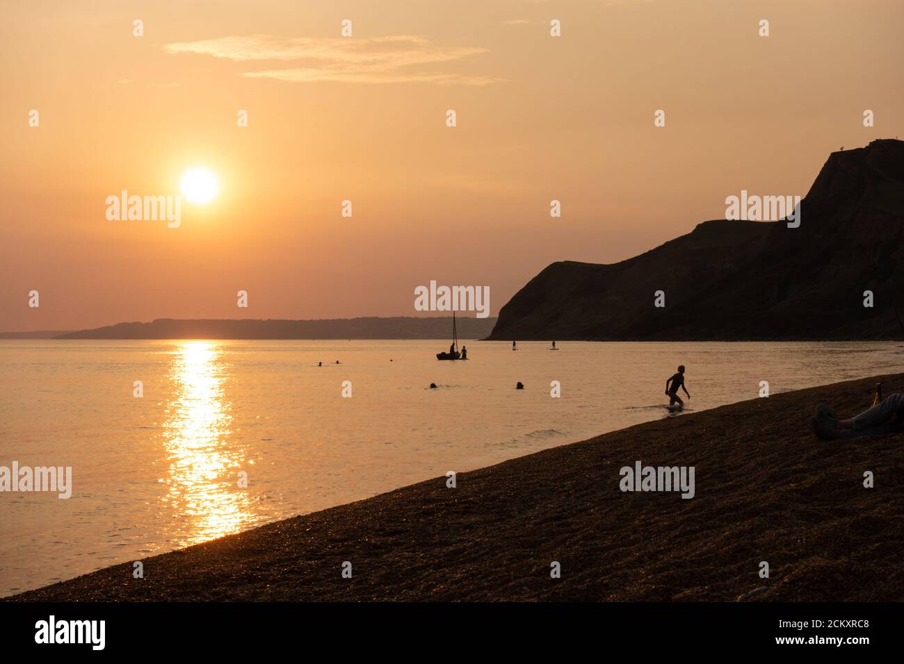 SUPs and a dinghy at Eype beach at sunset, Dorset, UK Stock Photo - Alamy