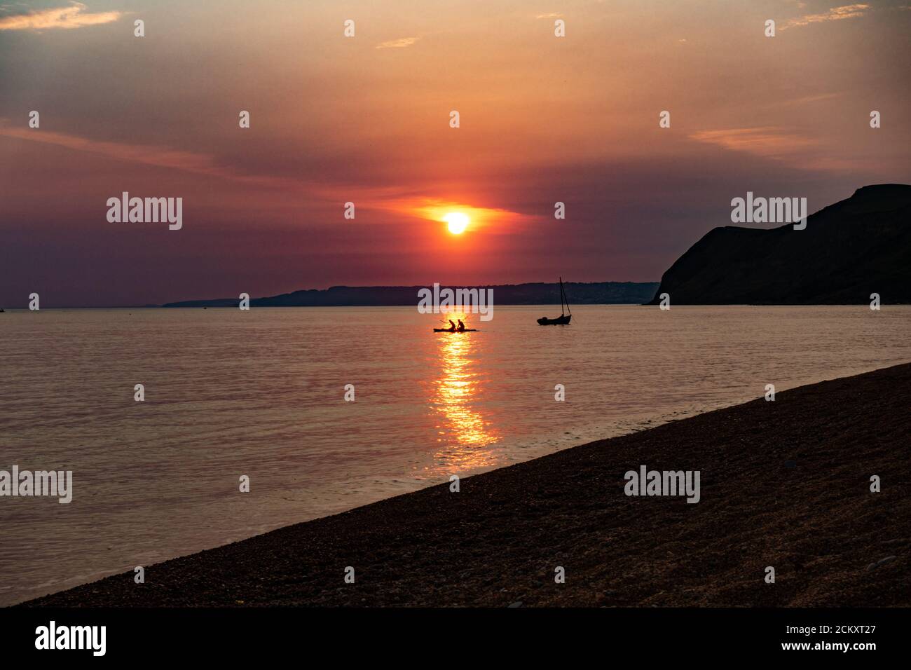 SUPs and a dinghy at Eype beach at sunset, Dorset, UK Stock Photo - Alamy