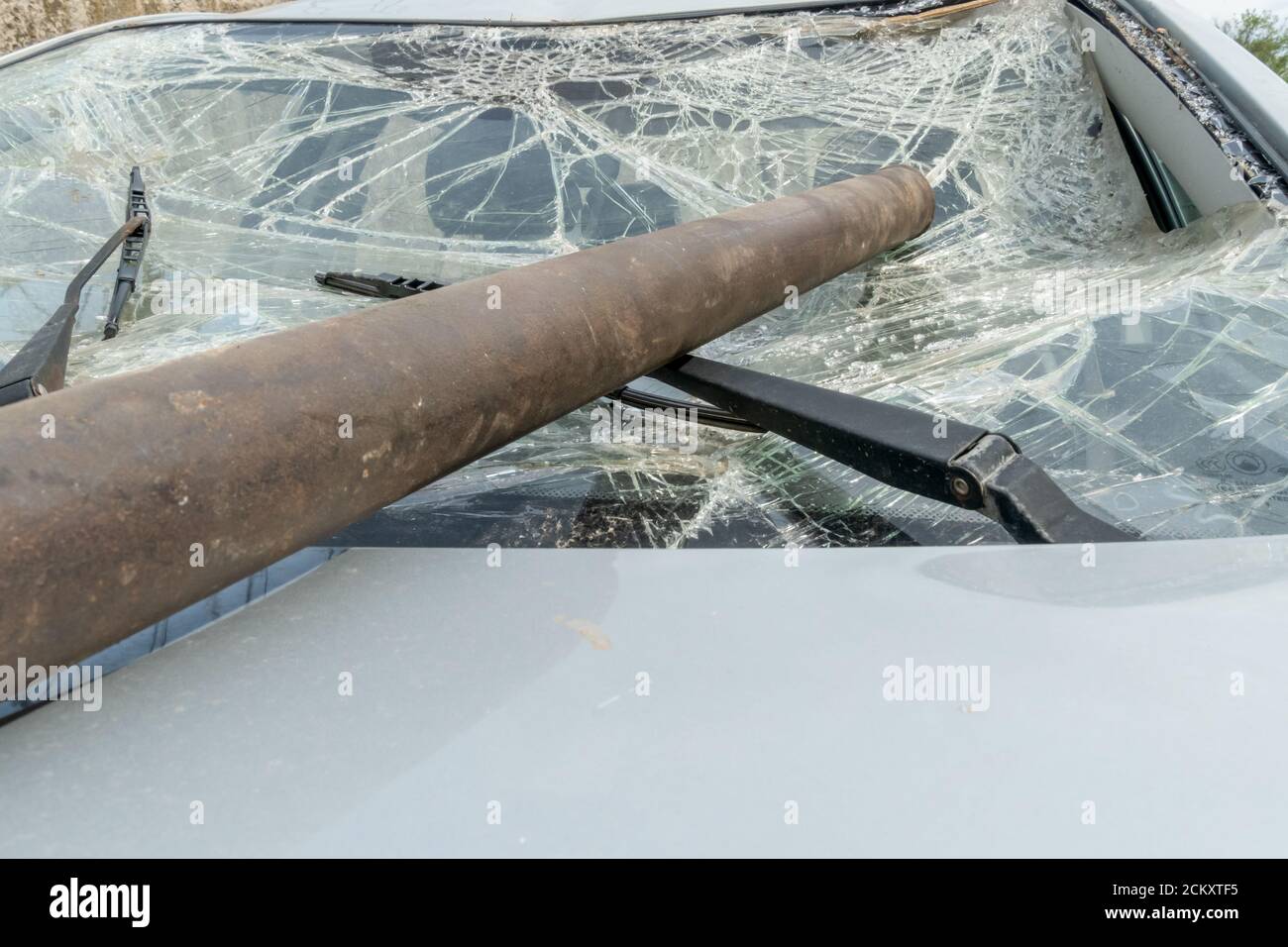 The iron pipe lies on the broken windshield of the car. Damage to the ...