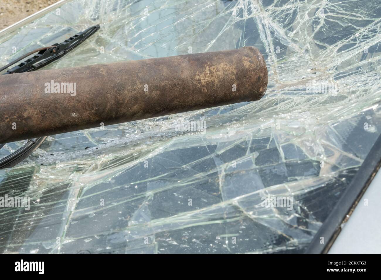 The iron pipe lies on the broken windshield of the car. Damage to the ...