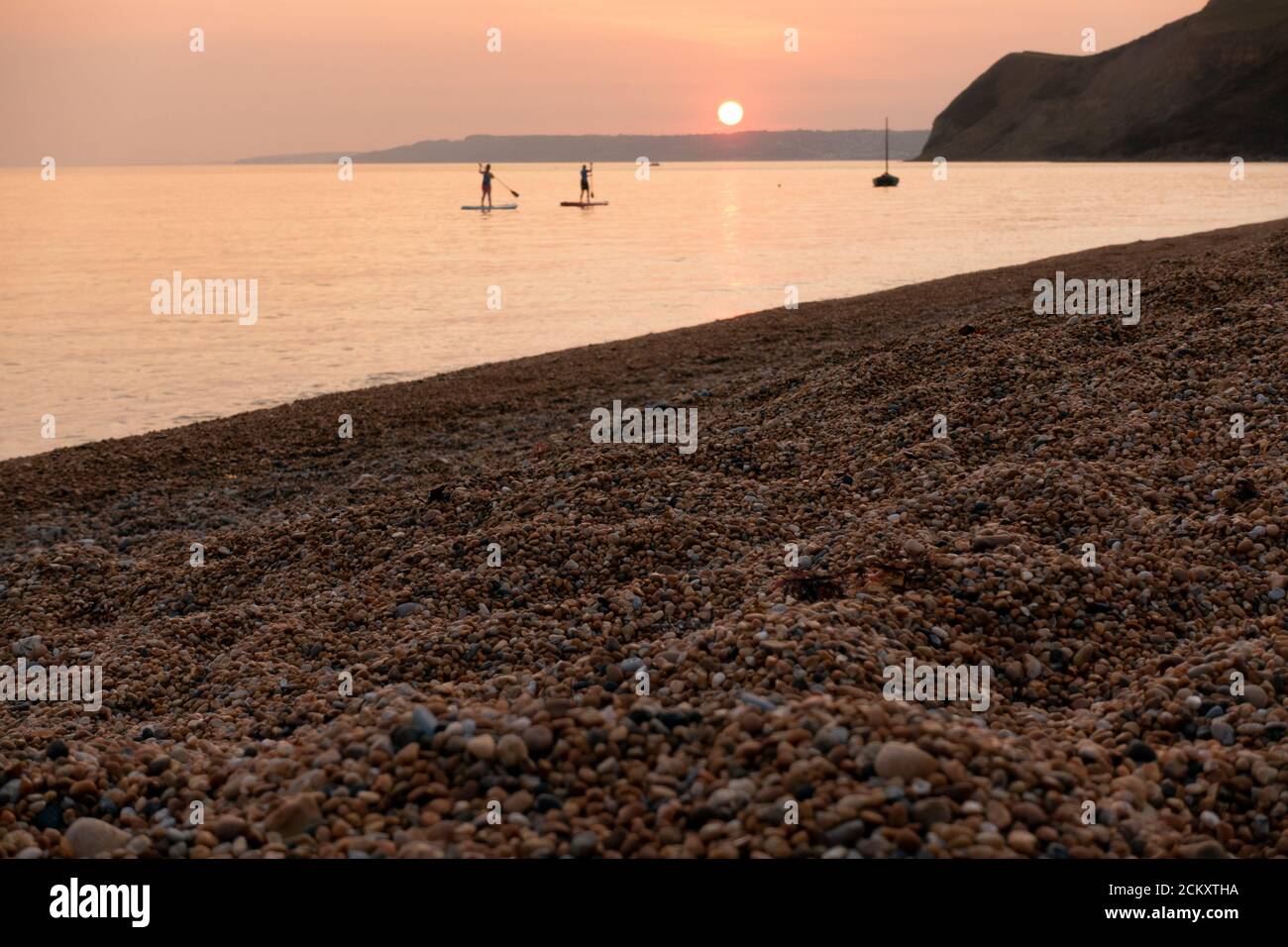 SUPs and a dinghy at Eype beach at sunset, Dorset, UK Stock Photo - Alamy