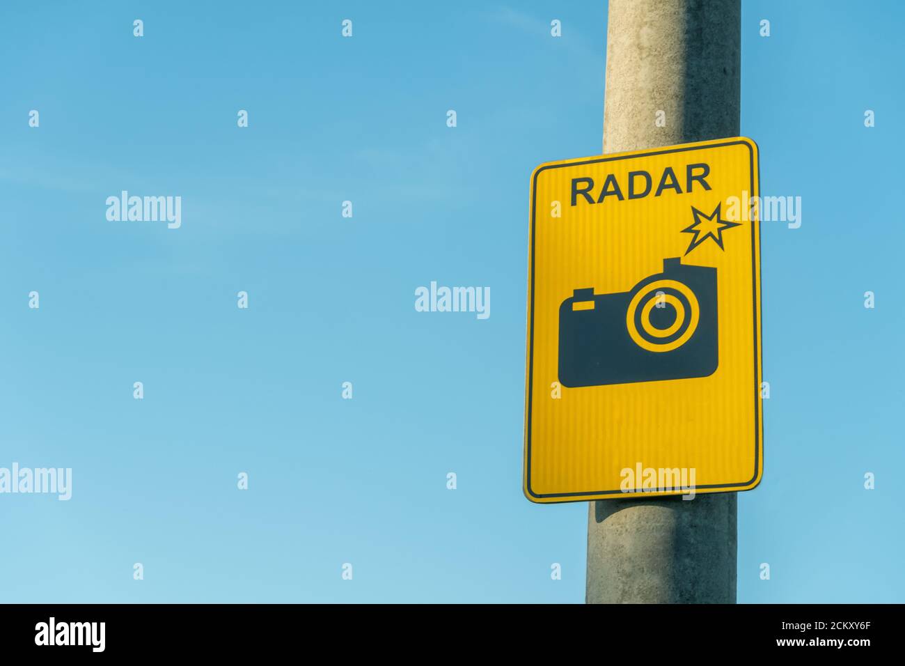 Yellow road sign "photo radar" on a pole close-up against the blue sky ...