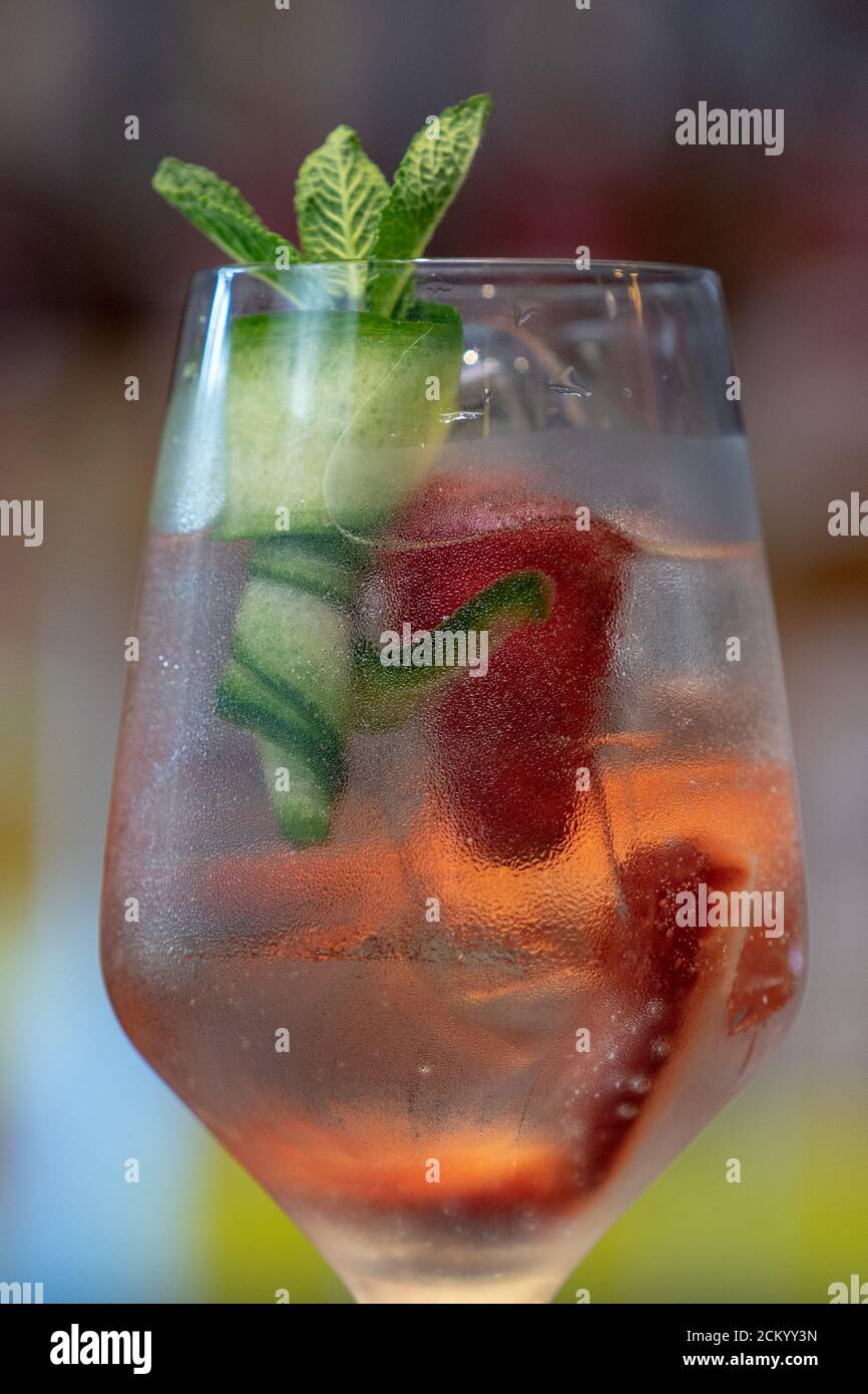Closeup shot of a glass of iced cocktail with strawberries and cucumber ...