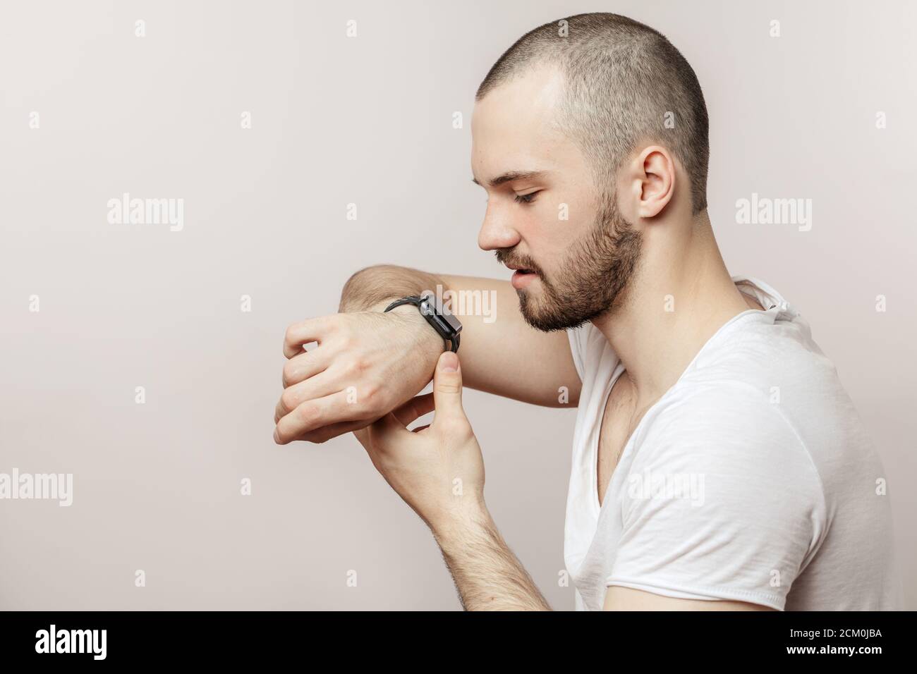 young handsome man looking at the new watch. close up side view ...