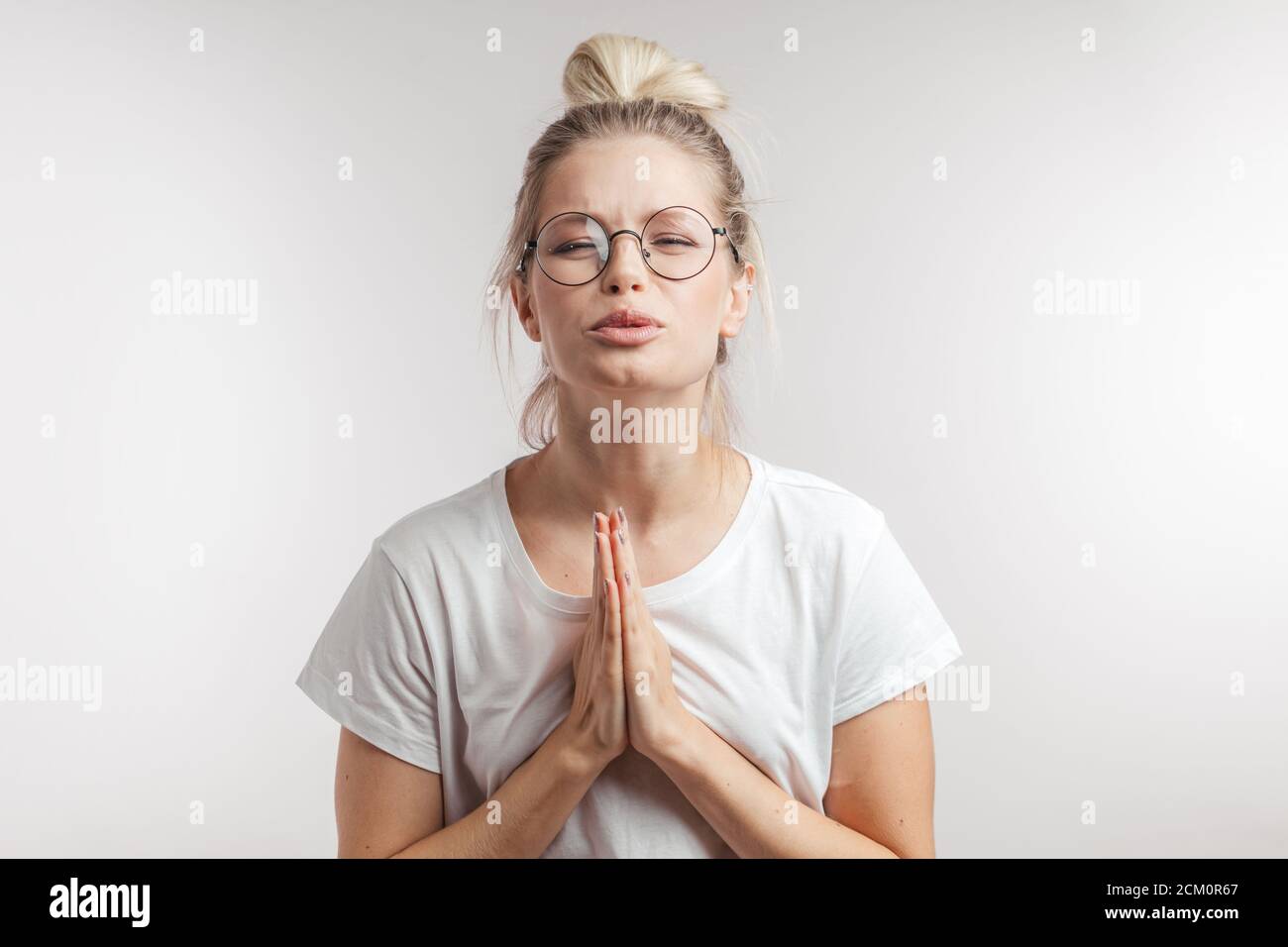 Scared or distressed young caucasian woman holding hands together and ...